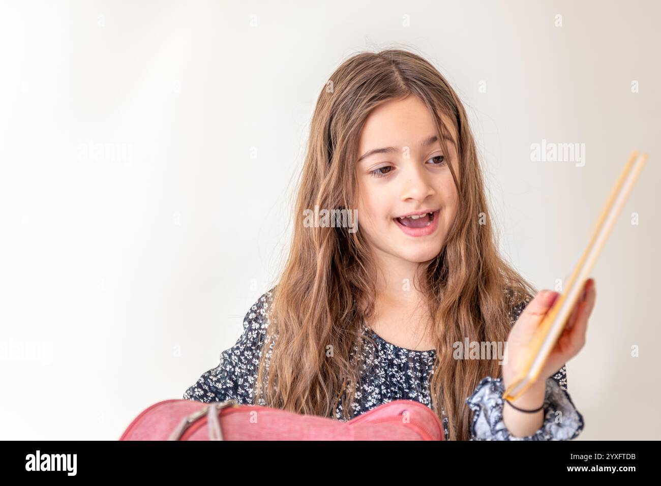 Happy girl is packing a backpack for school. The girl goes to school ...