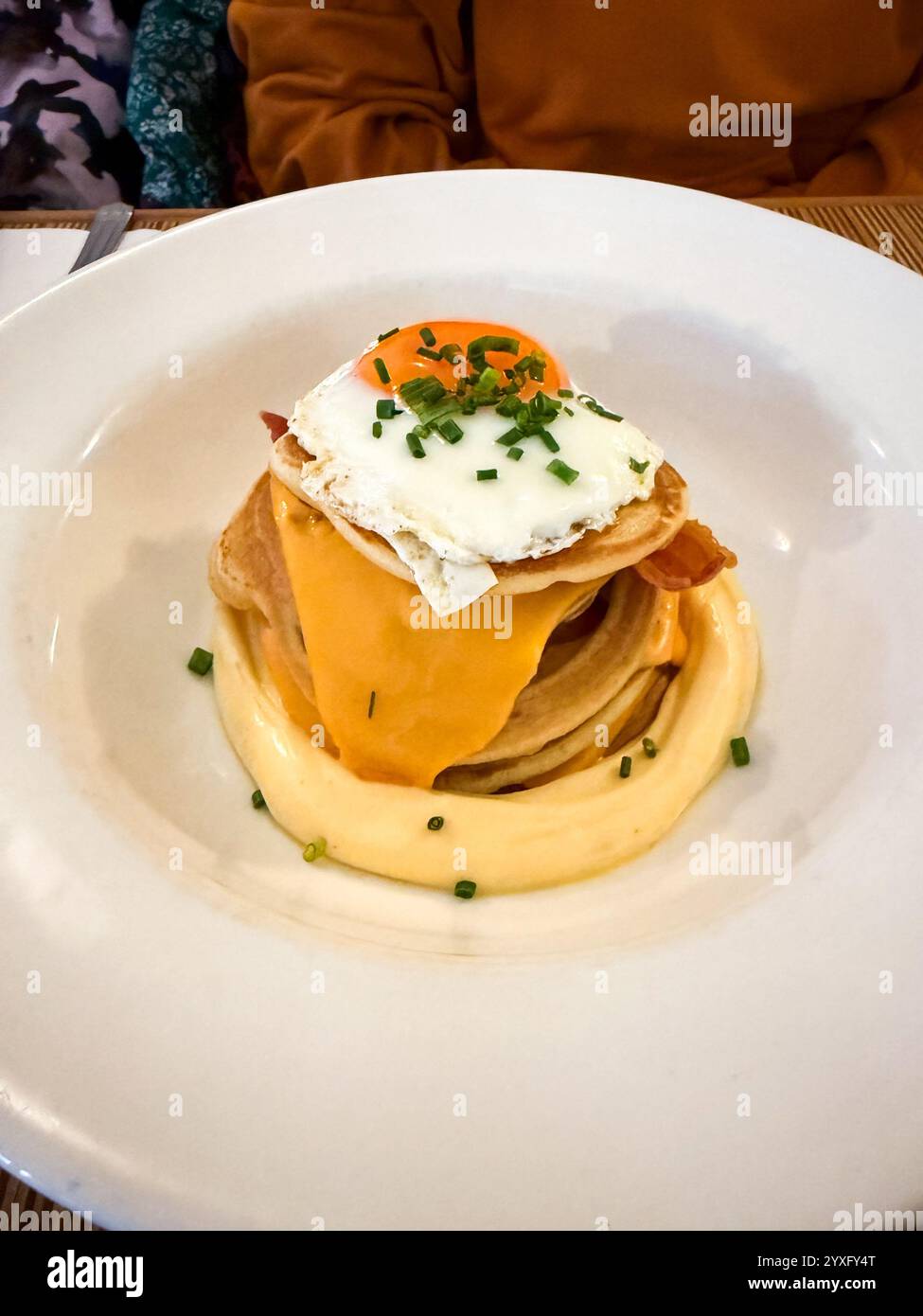 Salty pancake with egg, cheddar cheese sauce and bacon served at ...