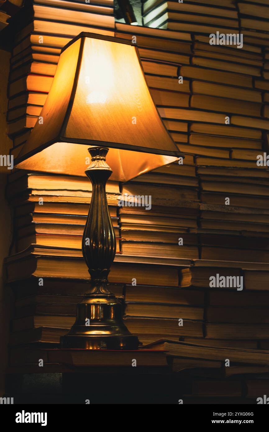 Retro lamp with warm light on antique bookshelf background. Pile of old ...