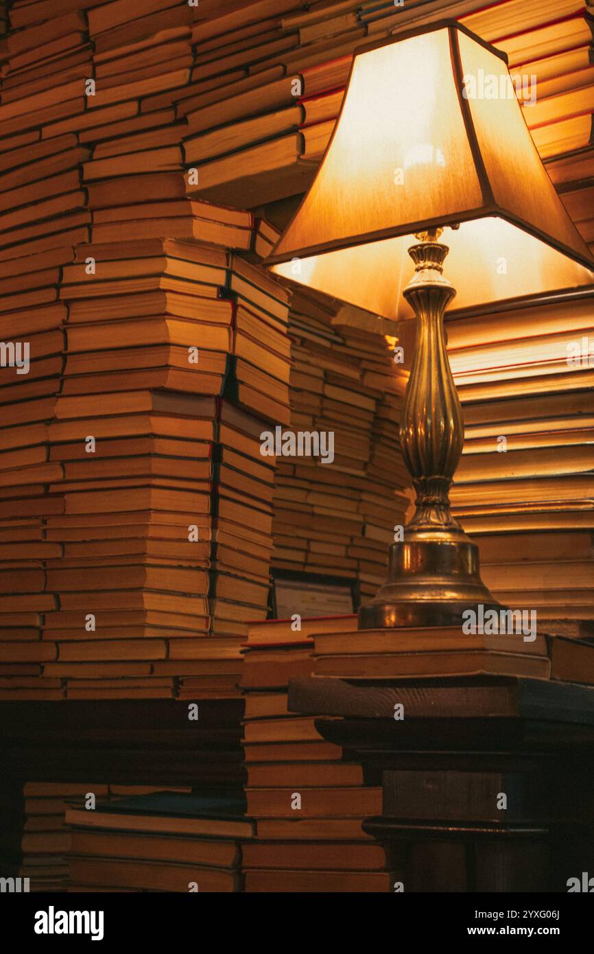 Retro lamp with warm light on antique bookshelf background. Pile of old ...