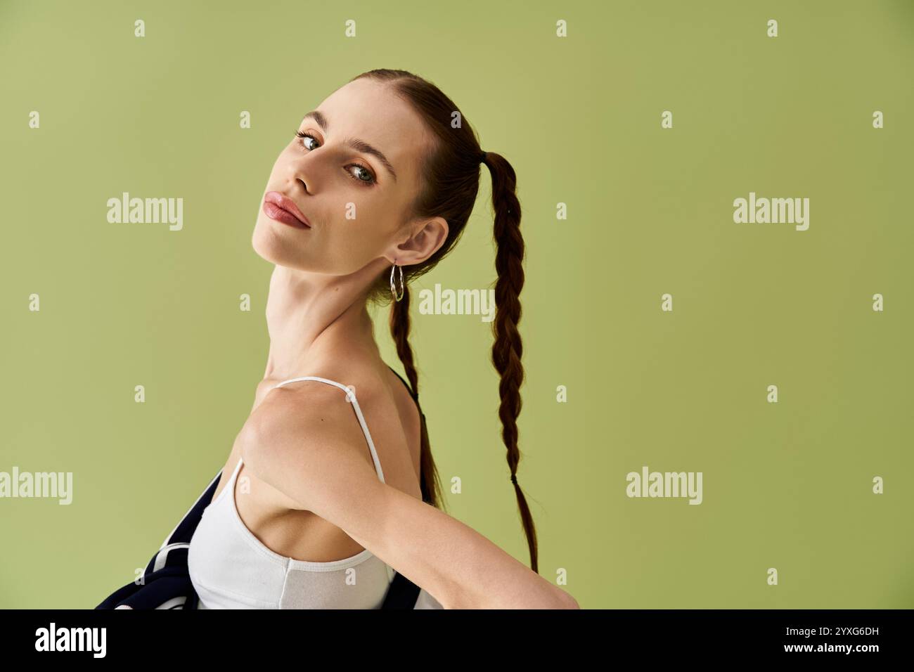 A young woman poses confidently against a green background, showcasing ...