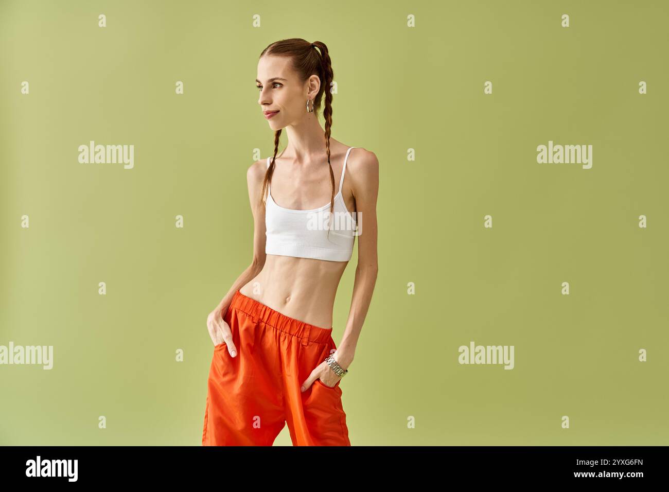A beautiful young woman poses against a green background, highlighting ...