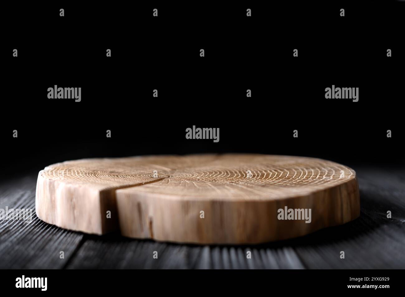 Round wooden plate with crack carved from tree trunk on black ...