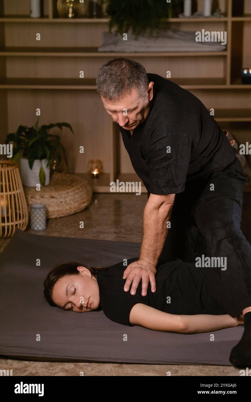 Girl in Thai massage session from therapist in massage room . Traditional Asian stretching ...