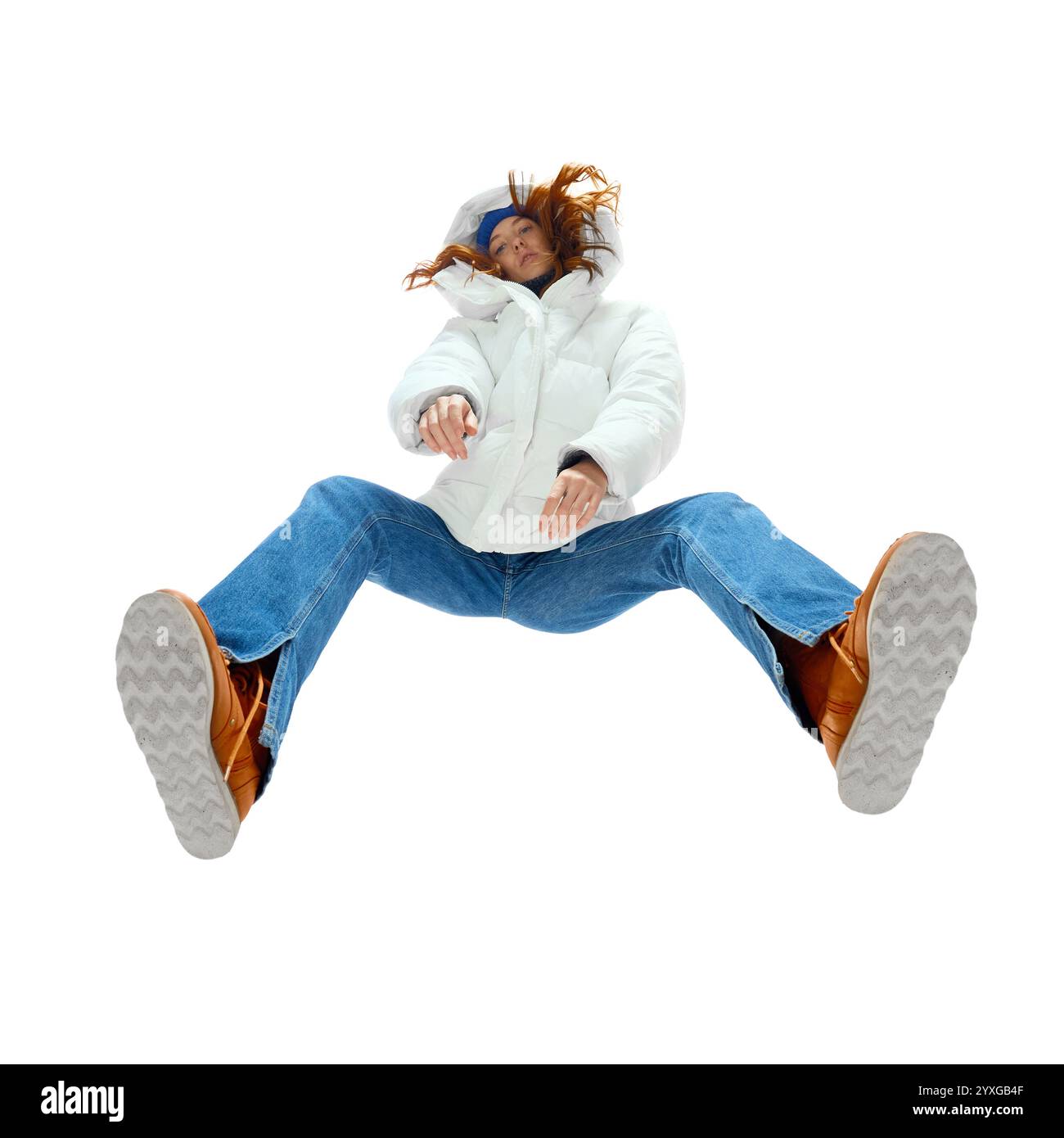 Bottom view image of young woman in white puffy jacket and jeans poses ...