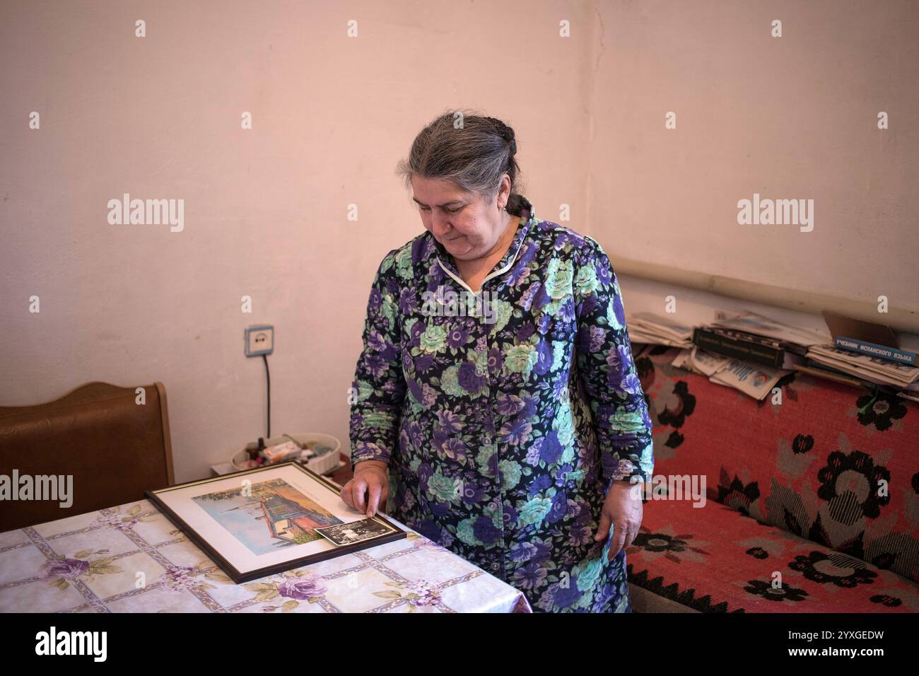 A Crimean Tatar woman in her home looks at a picture of her family's ...