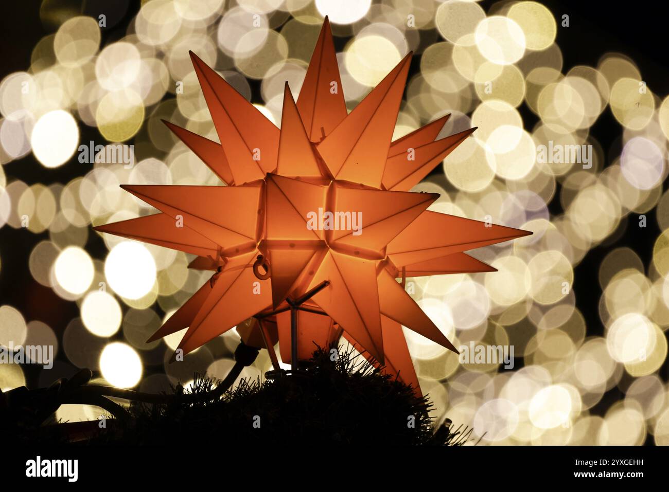 An orange-coloured, Christmassy star shines in the foreground in front ...
