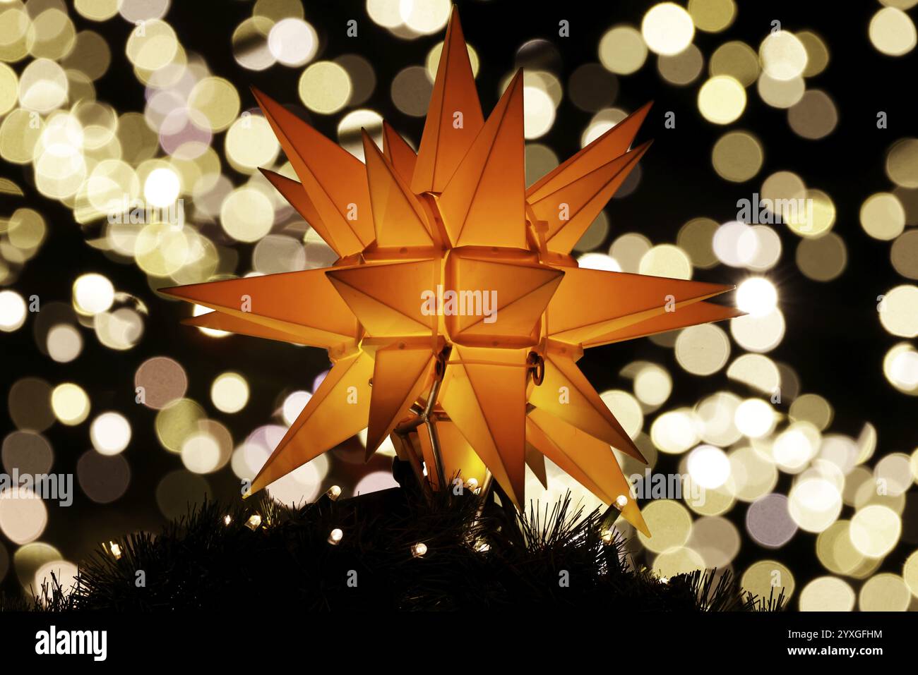 An orange-coloured, Christmassy star shines in the foreground in front ...