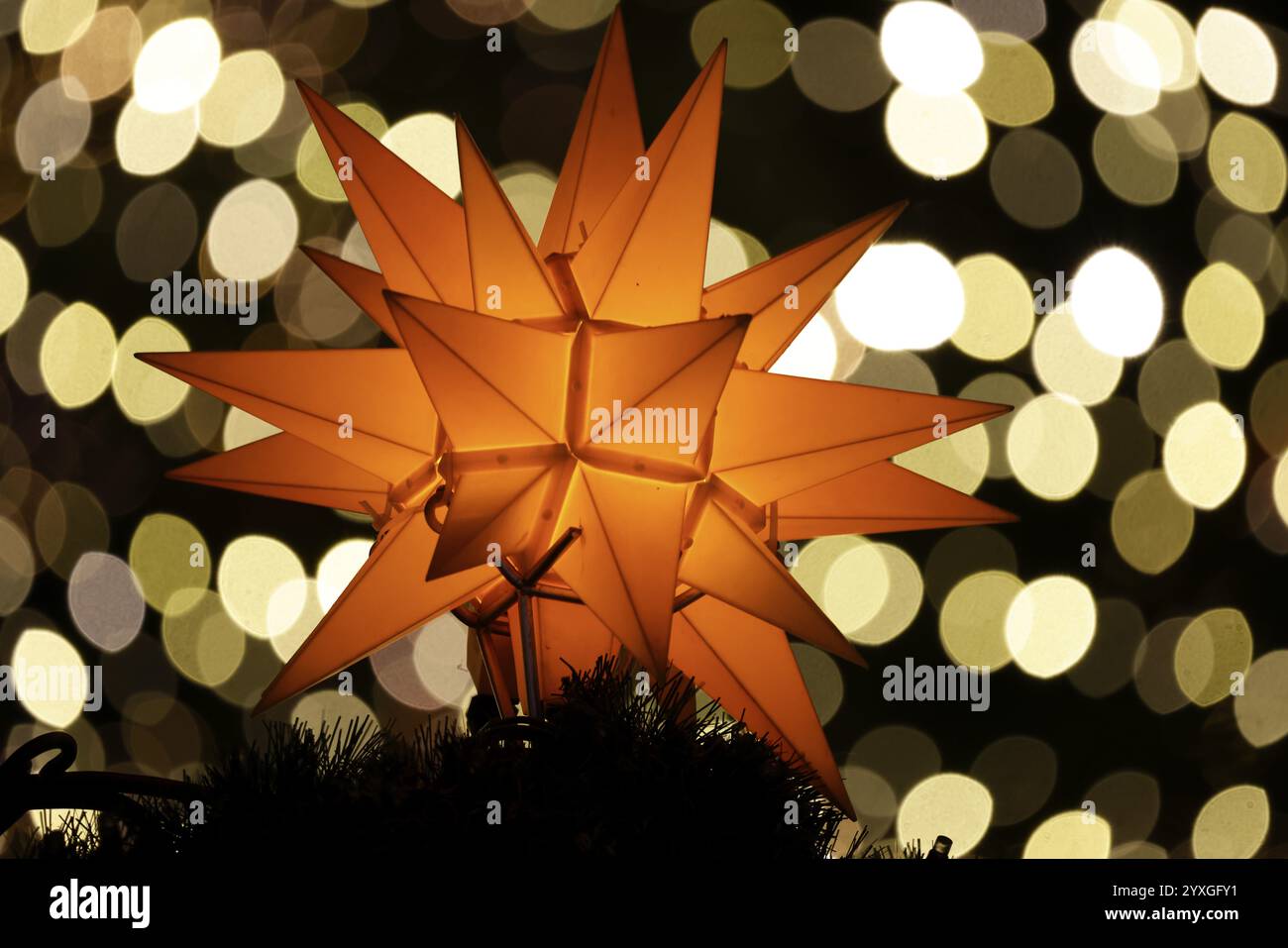 An orange-coloured, Christmassy star shines in the foreground in front ...