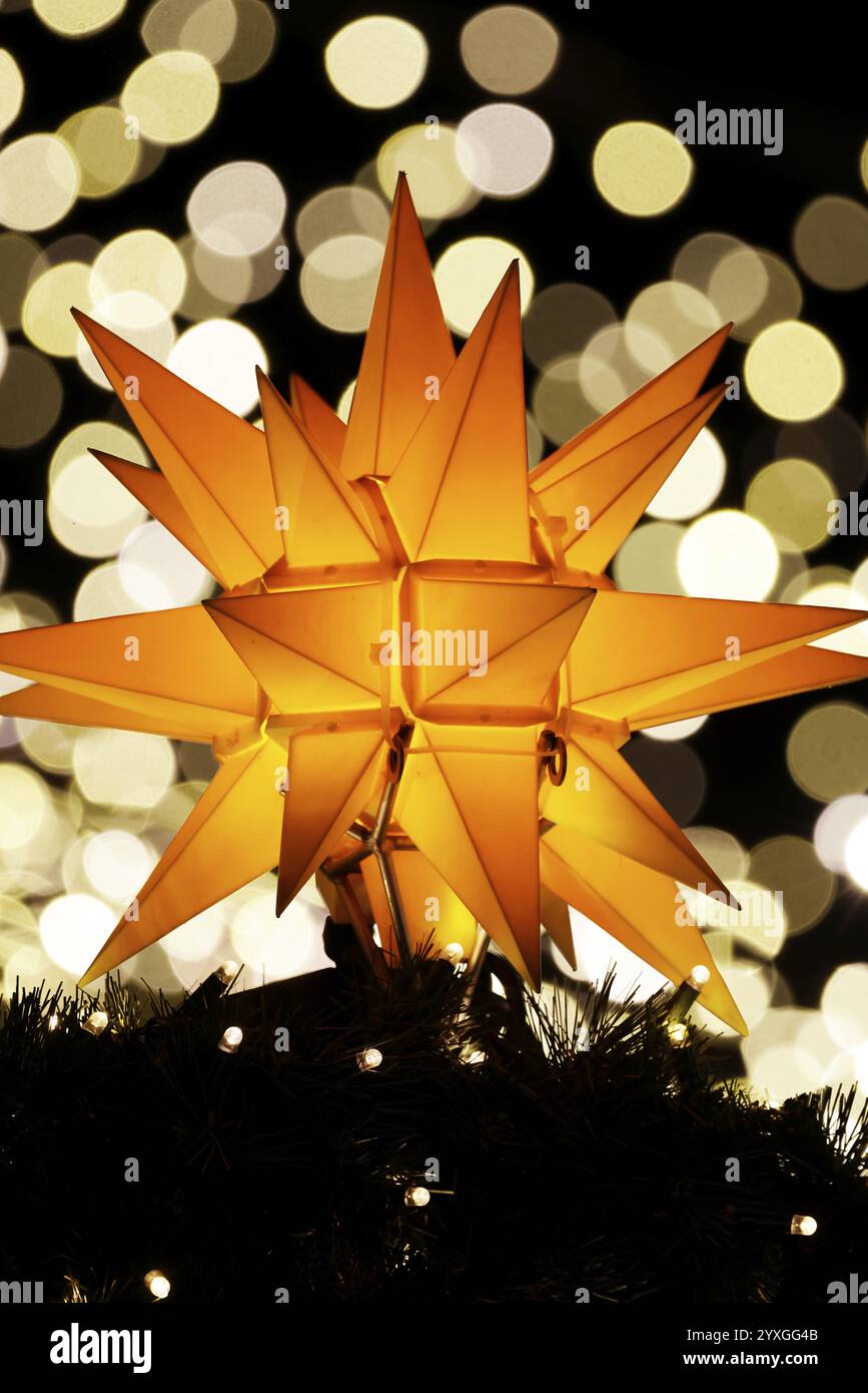 An orange-coloured, Christmassy star shines in the foreground in front ...