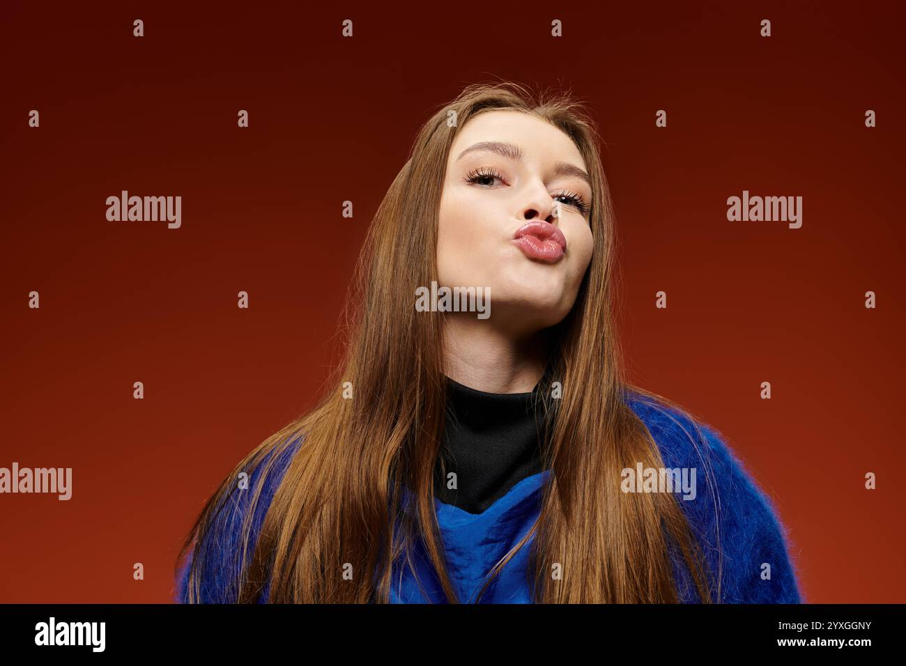 A vibrant stylish woman playfully purses her lips in front of a warm ...