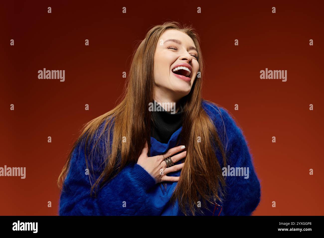 A vibrant stylish woman wearing a blue coat shares a joyful laugh ...