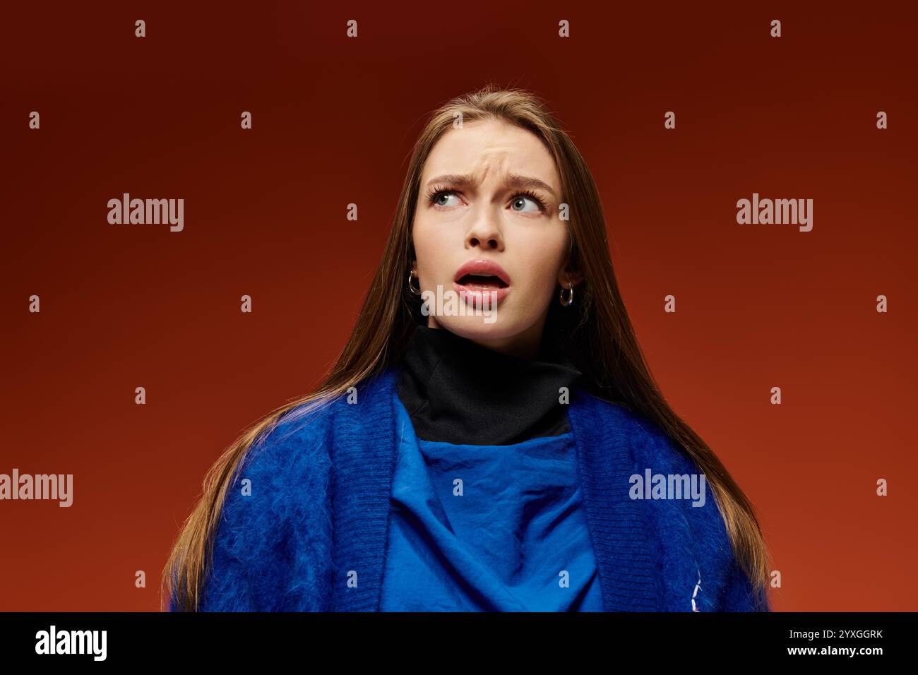 A vibrant stylish woman with long hair looks upwards with a surprised ...