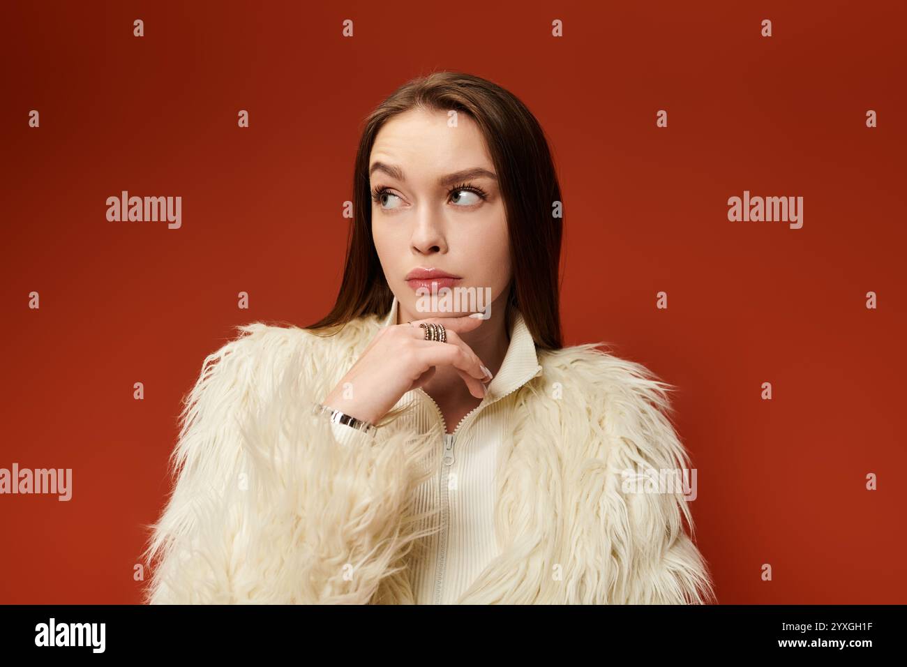 A stylish woman poses thoughtfully in a chic faux fur jacket against a ...