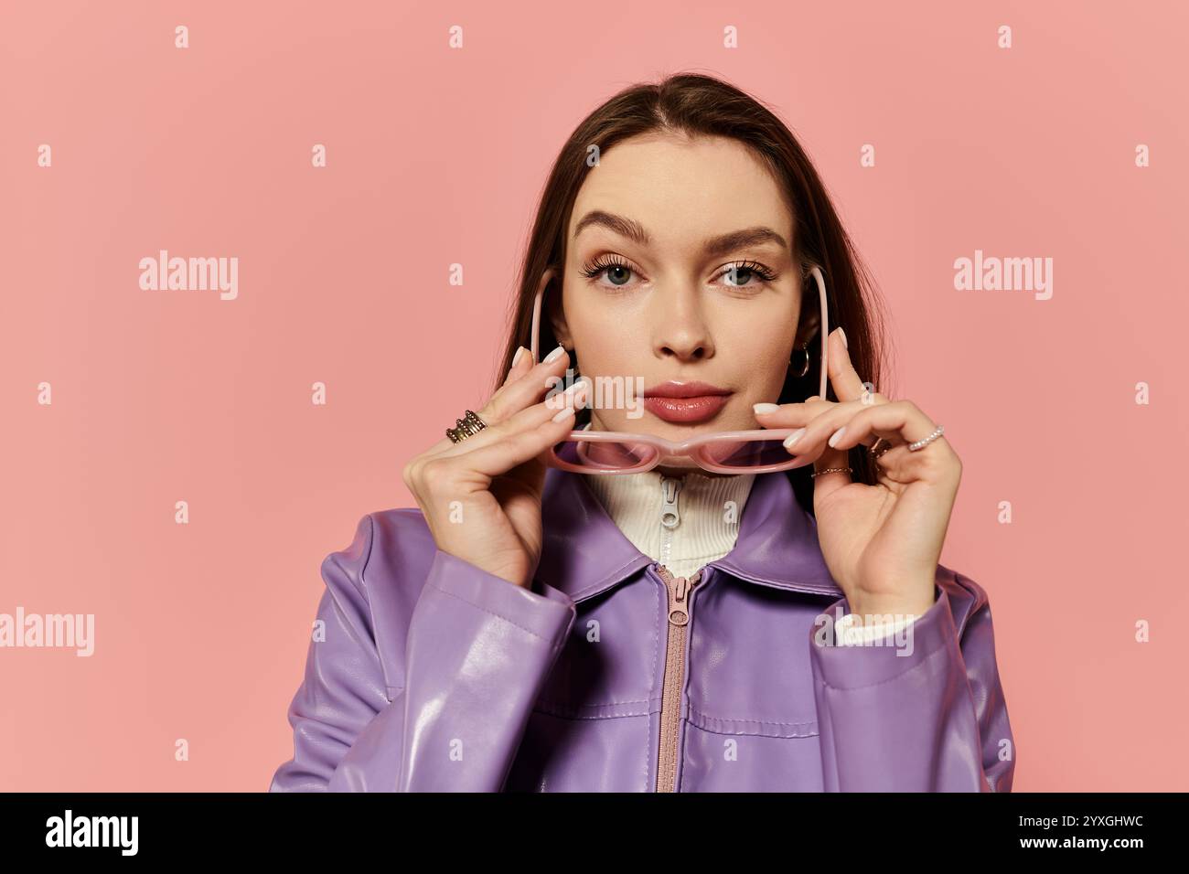 A vibrant woman adjusts her glasses while showcasing her stylish outfit ...