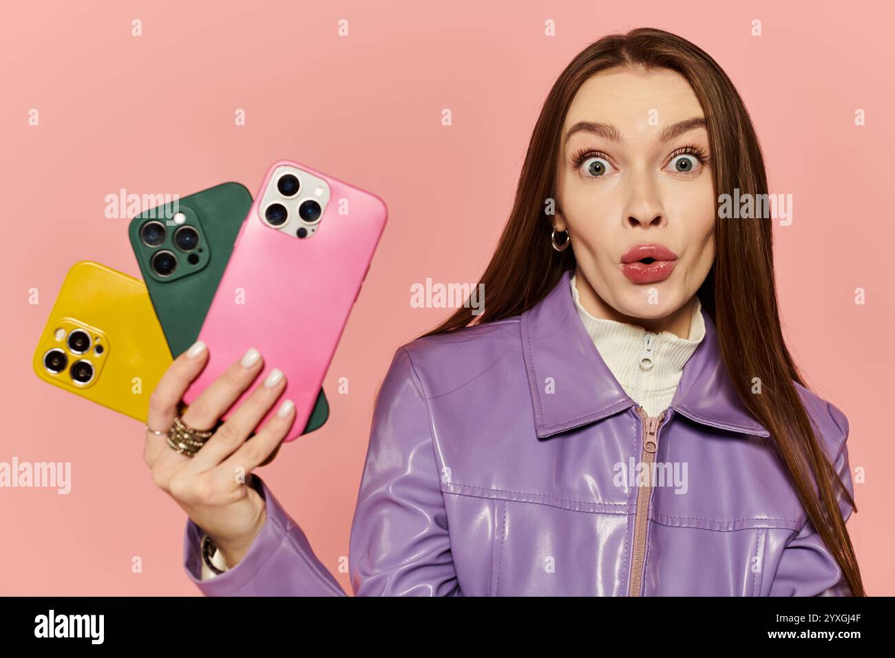 A stylish woman holds four colorful smartphones while expressing ...