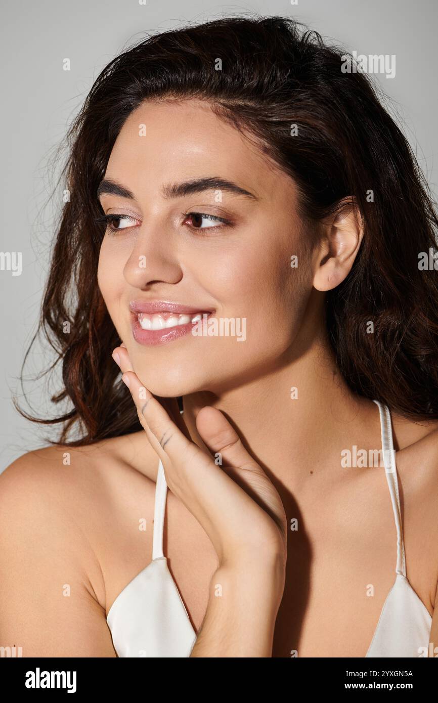 Beautiful young woman showcases her joy and charm while touching her ...