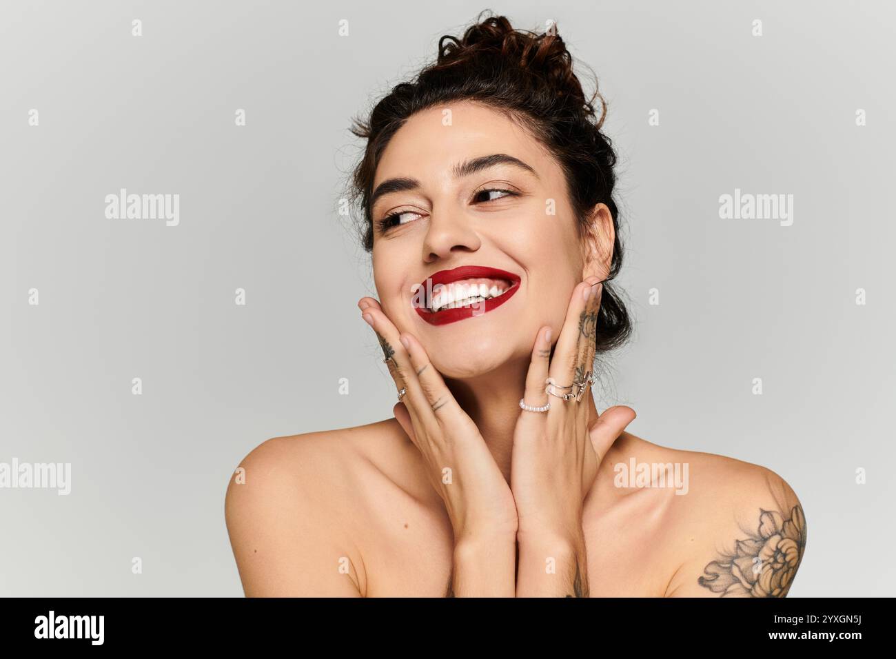 A young beautiful woman with a radiant smile poses with joy in a simple ...