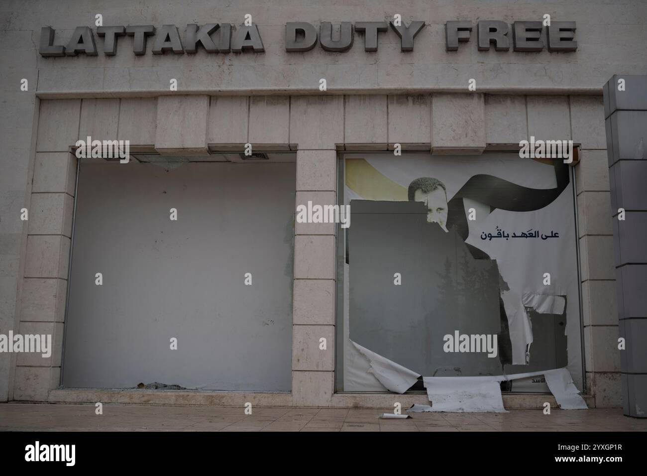 A damaged shop window with an image depicting Bashar Assad is seen at ...