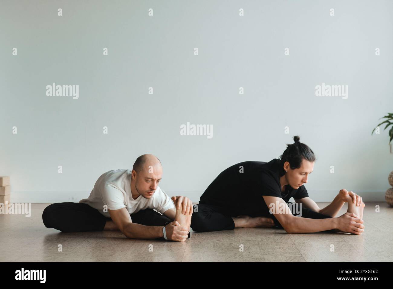 two young athletes practice yoga in the gym. Joint training, indoors ...