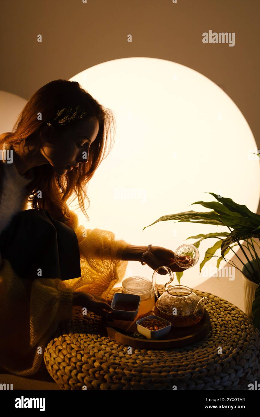 A young girl conducts an evening tea drinking procedure indoors ...