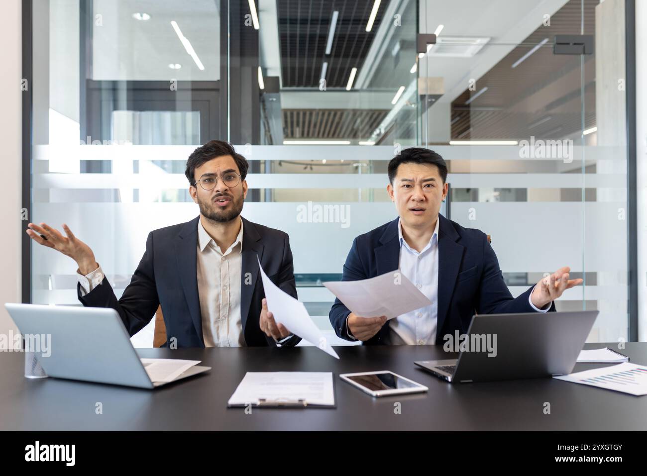 Two business professionals sitting in a modern office, visibly ...