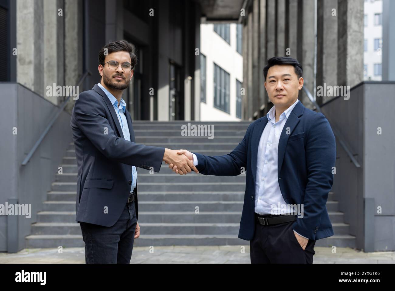 Two professionals engage in a business handshake outdoors, signifying ...
