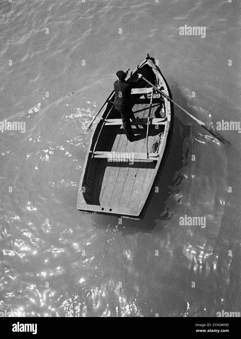 A sailor pulls on the oars of a rowing boat, seen from above, 1930's ...