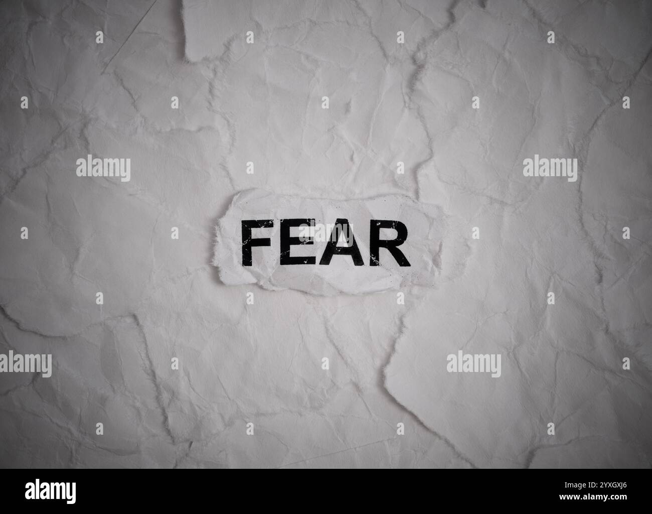 Crumpled piece of paper with word Fear on torn white paper pieces ...