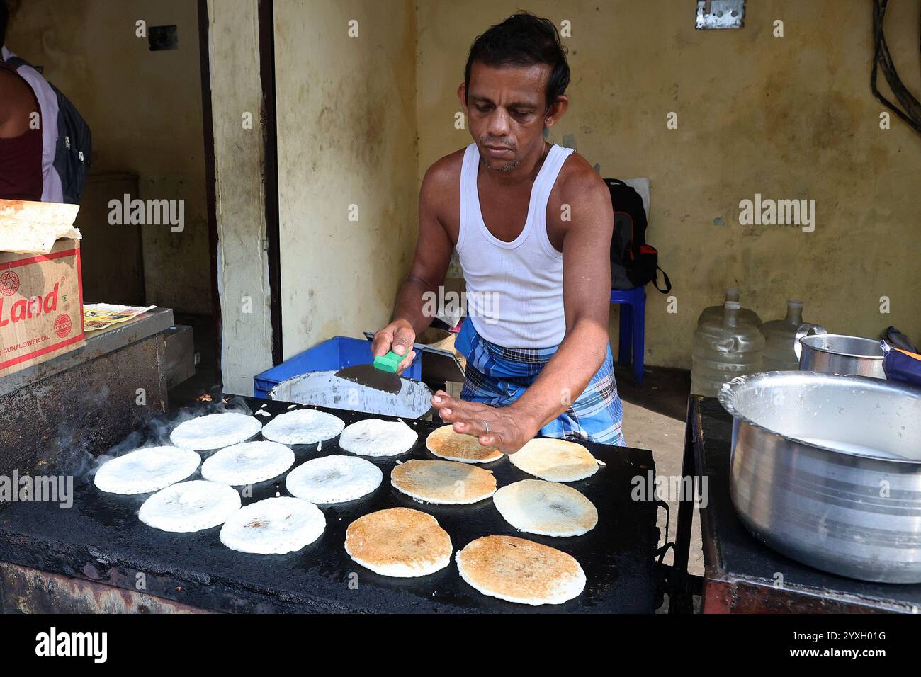 Vendor making dosa at a food stall in the George Town district of ...