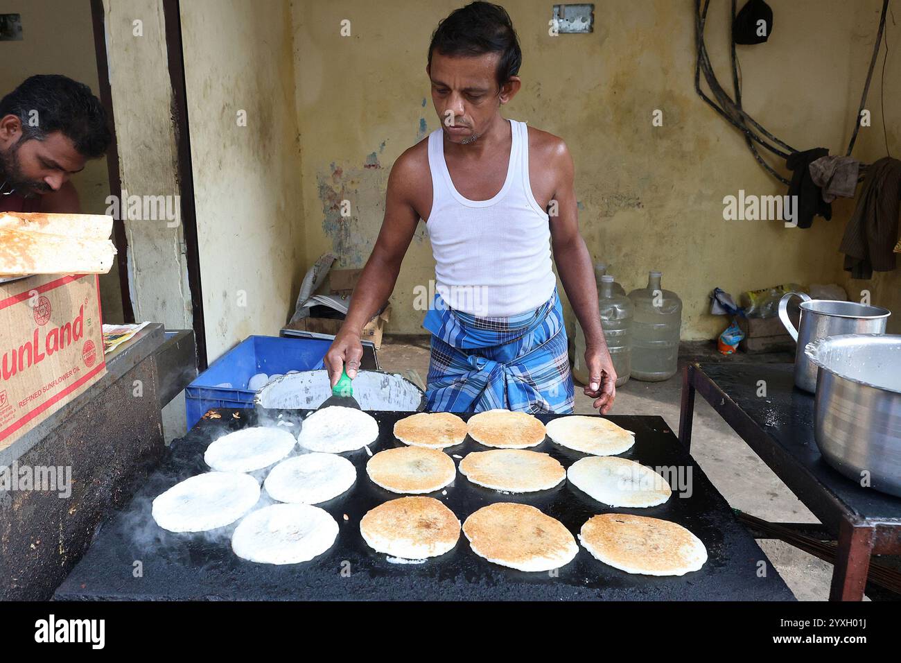 Vendor making dosa at a food stall in the George Town district of ...
