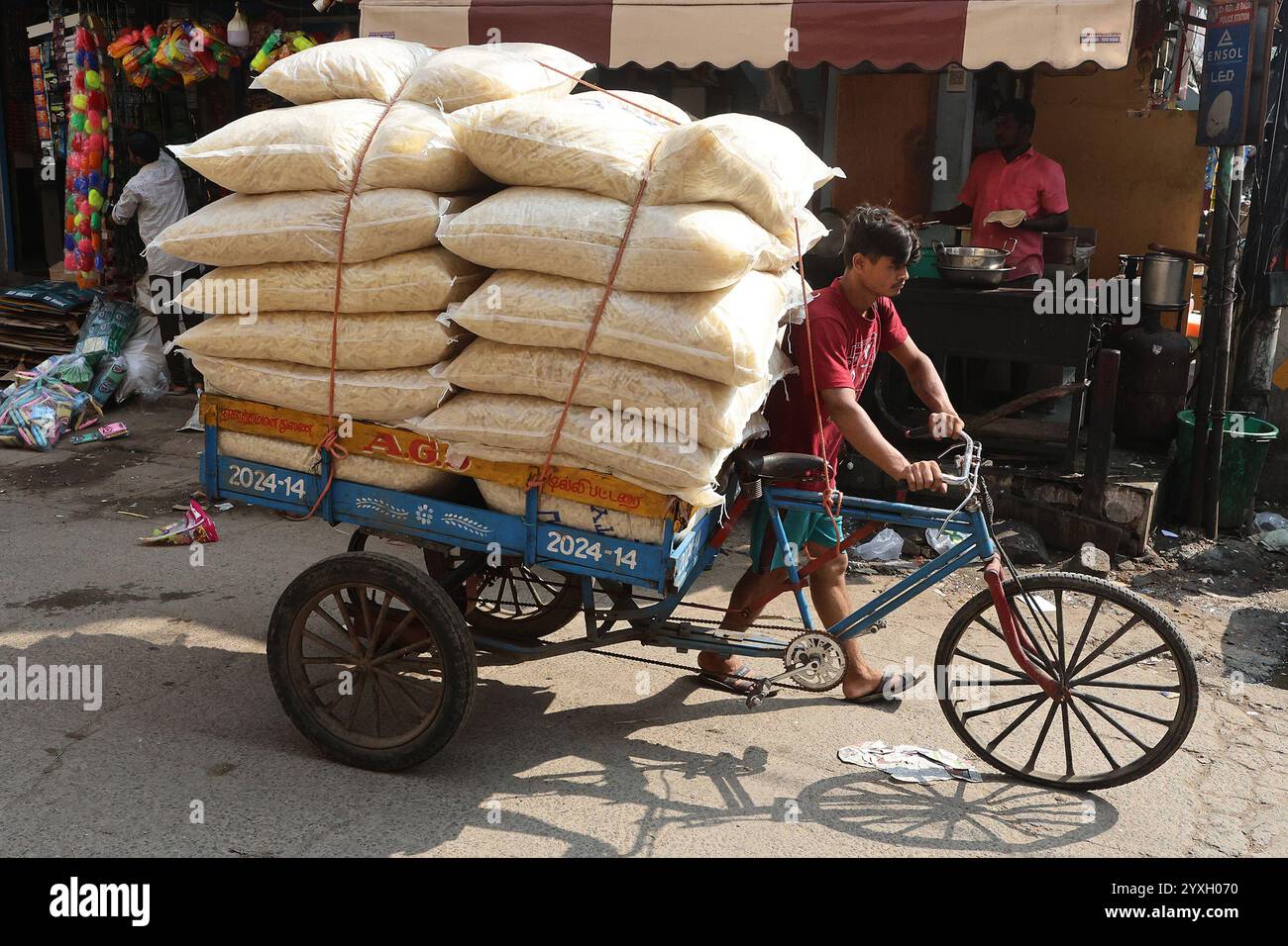 A coolie pushes a bicycle cart loaded with goods through the George ...