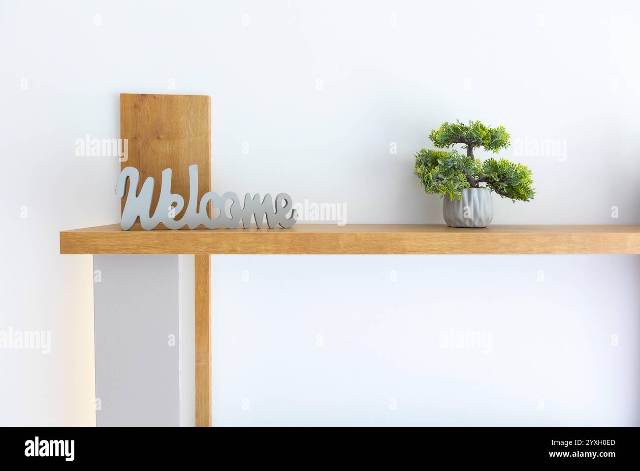 Cursive welcome sign and bonsai plant on the shelf, hotel or home decor ...