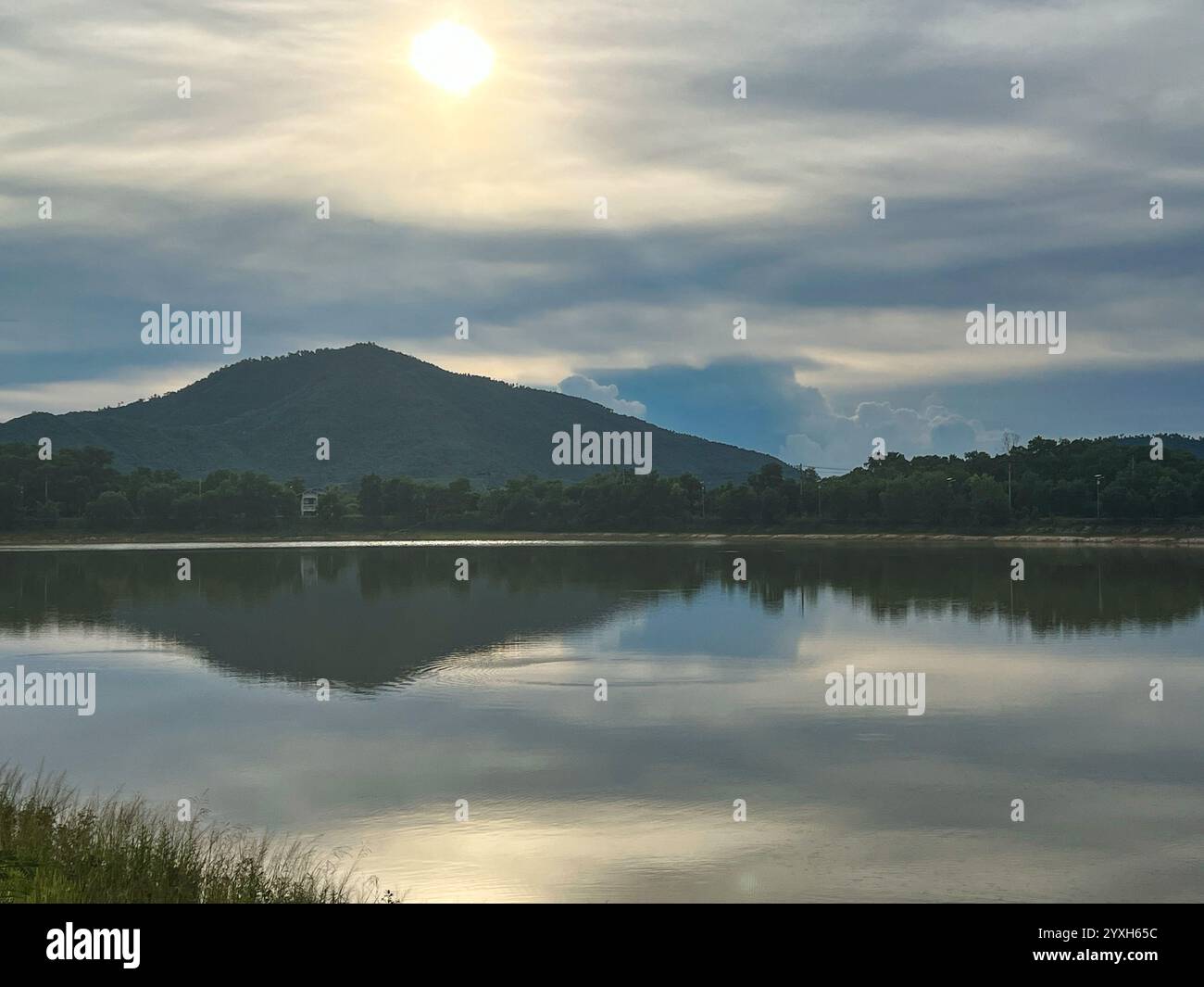 Description: Tranquil lake view with mountain silhouette and cloudy sky reflecting in still ...