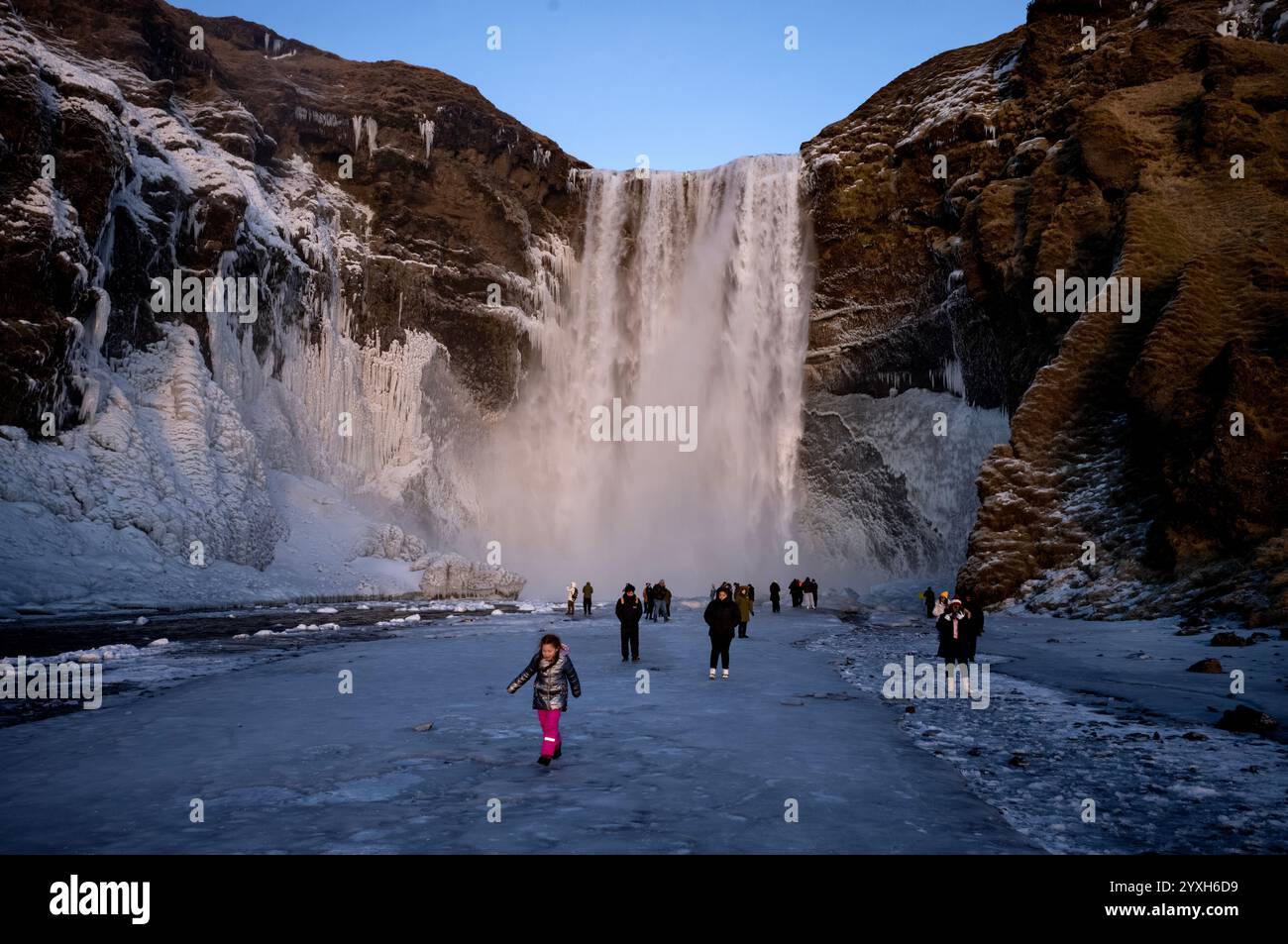 Visitors stand along the frozen and ice covered waters bellow the ...