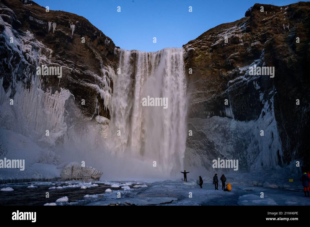 Visitors stand along the frozen and ice covered waters bellow the ...