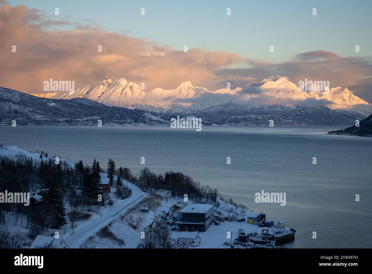 Mountains lined by calm water of the Norwegian sea. Colorful clouds in ...