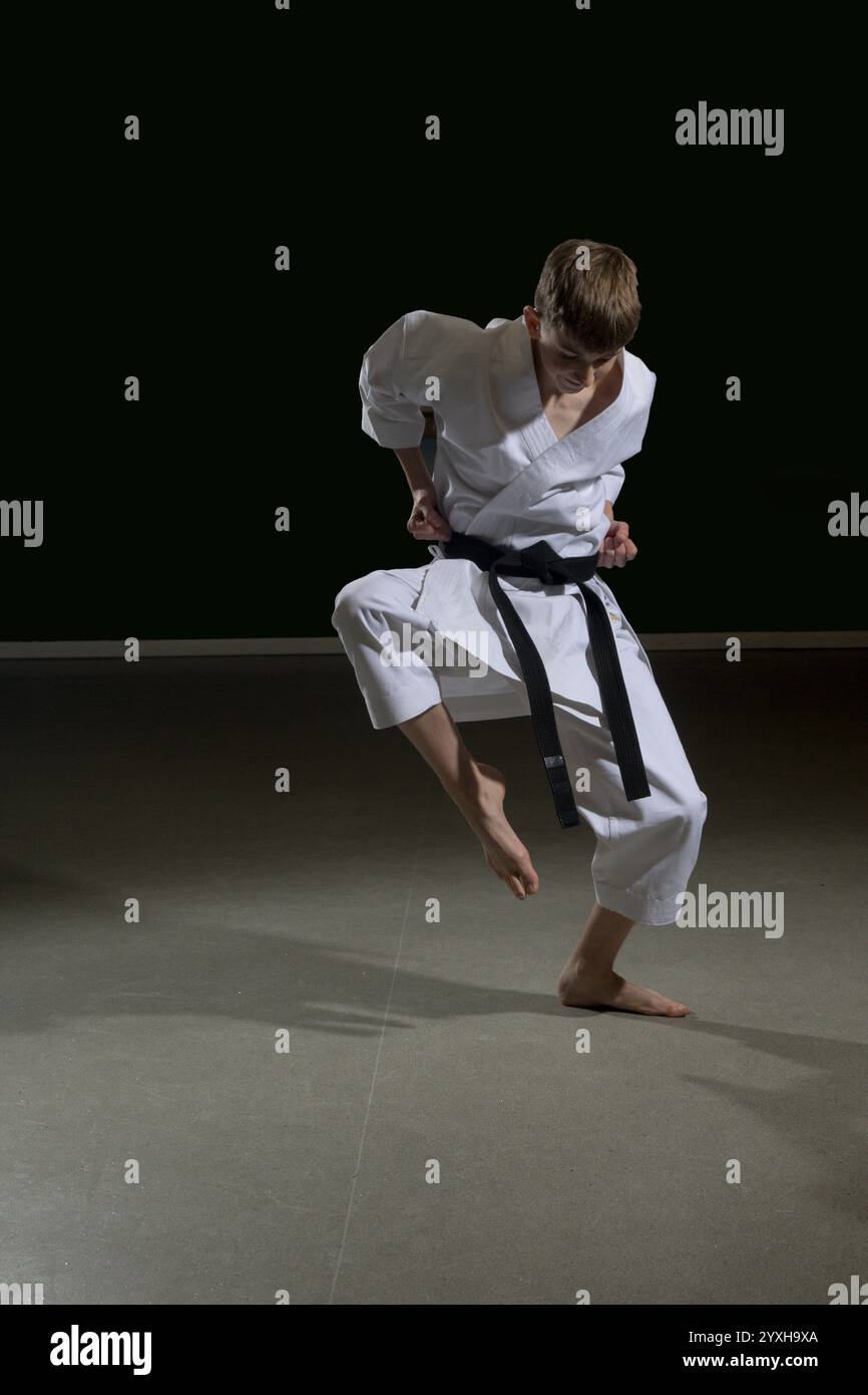 Fifteen year old male teenage karate black belt performing kata Seipai ...
