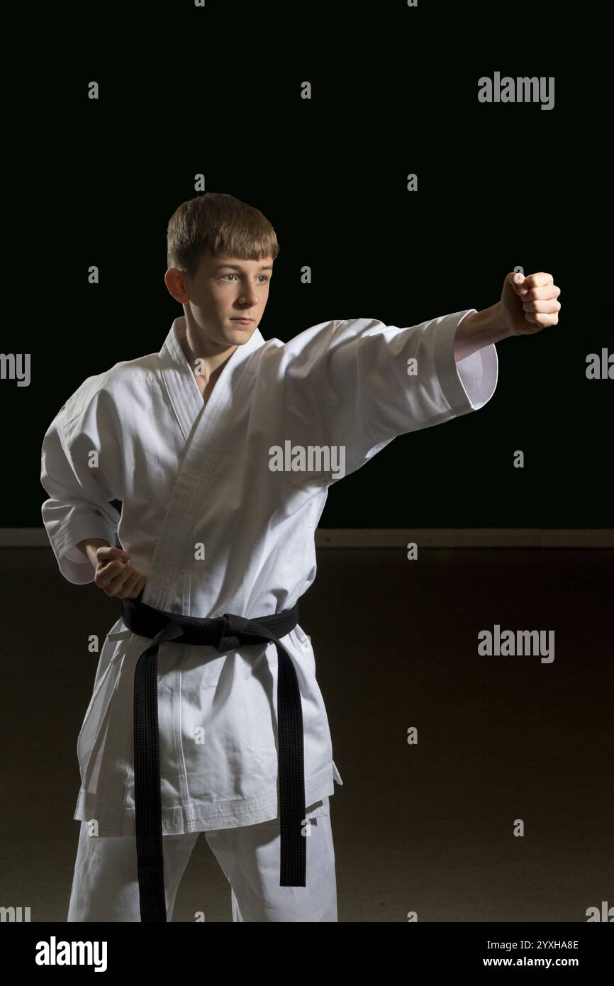 Fifteen year old male teenage karate black belt doing a back fist ...