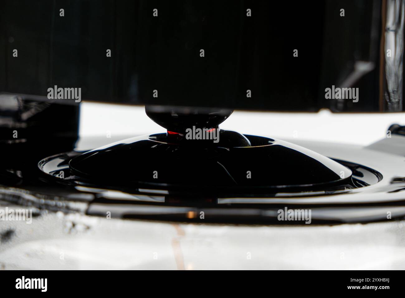 A coffee maker with a black lid and silver base is filled with coffee ...