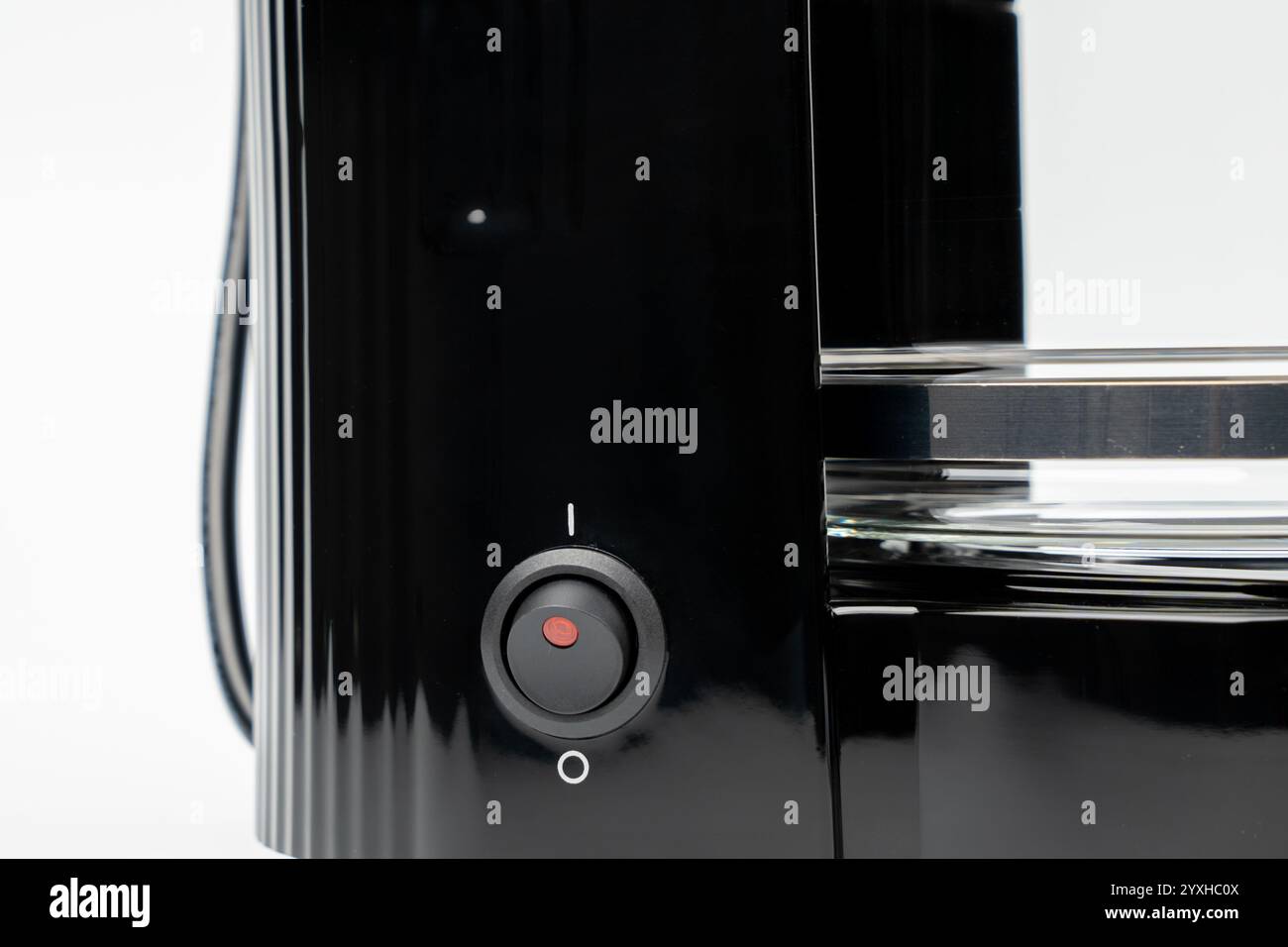 A black coffee maker with a red button on the side. The button is ...