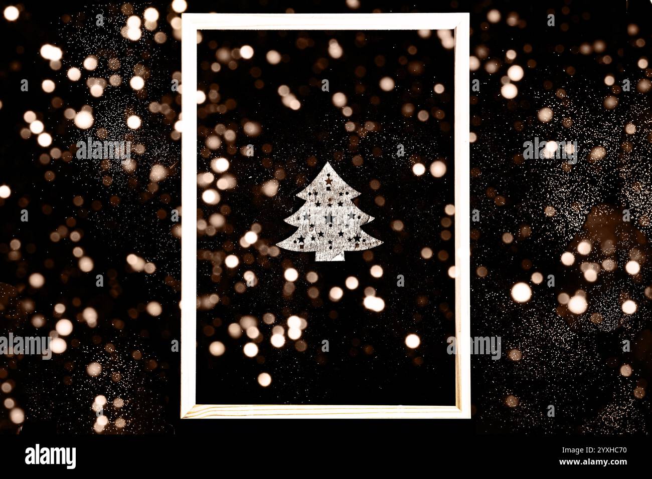 Wooden Christmas tree in a frame on black background and blurred fairy ...