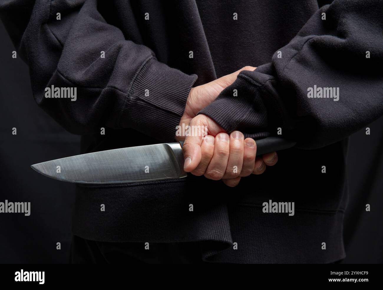 Criminal hiding a knife behind his back, man holding a weapon with both ...