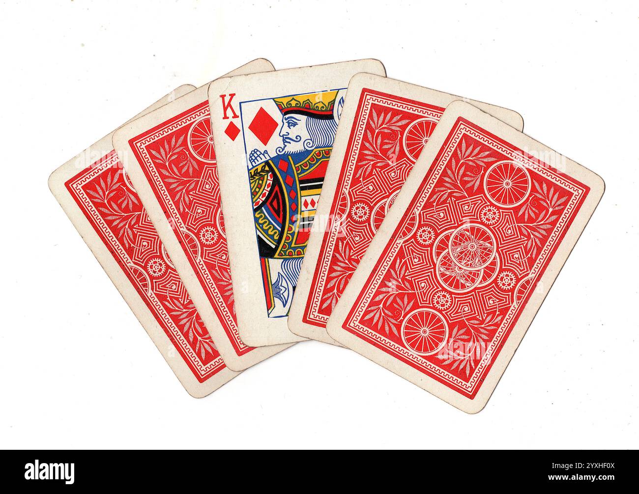 A hand of vintage playing card backs with the king of diamonds revealed ...