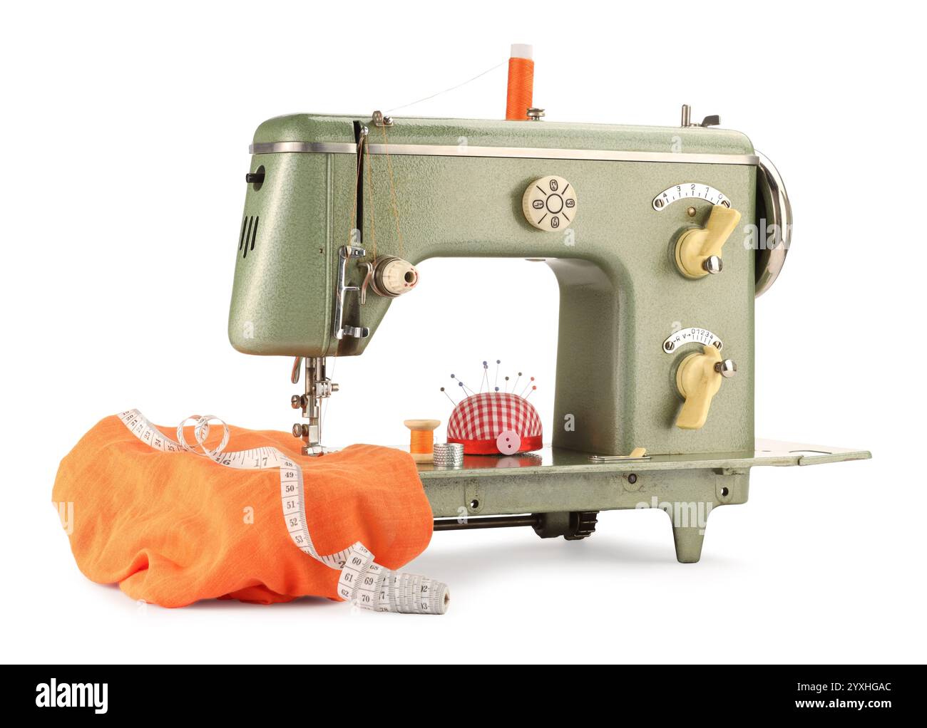 Sewing machine with orange fabric, measuring tape, pincushion and ...