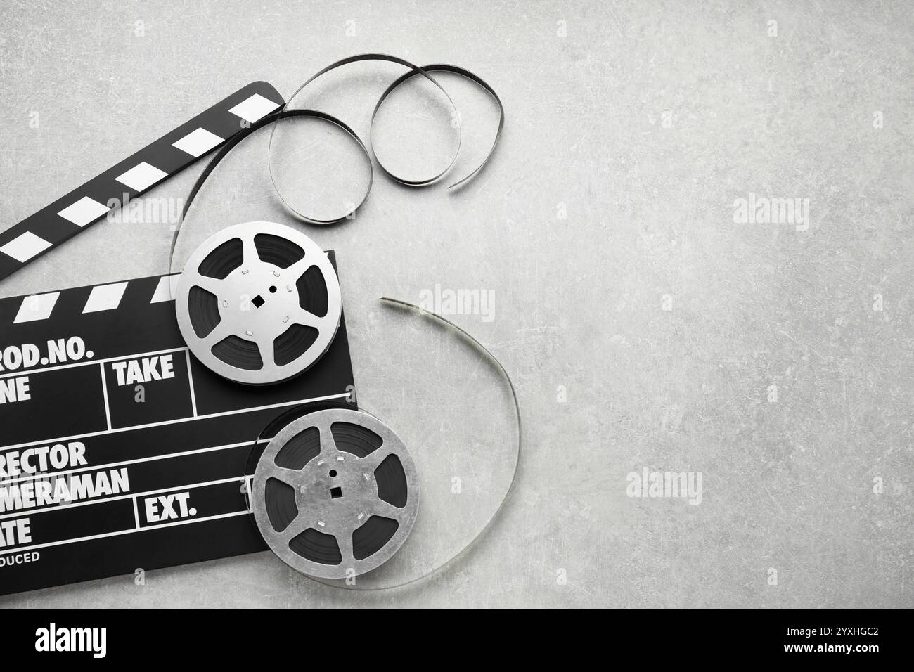 Movie clapper and film reels on grey textured table, top view. Space ...