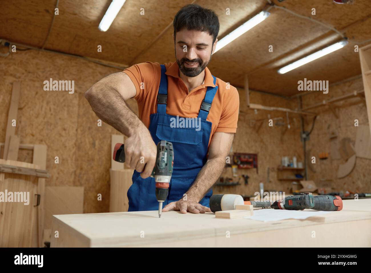 Carpenter working with drill making holes in plank Stock Photo - Alamy