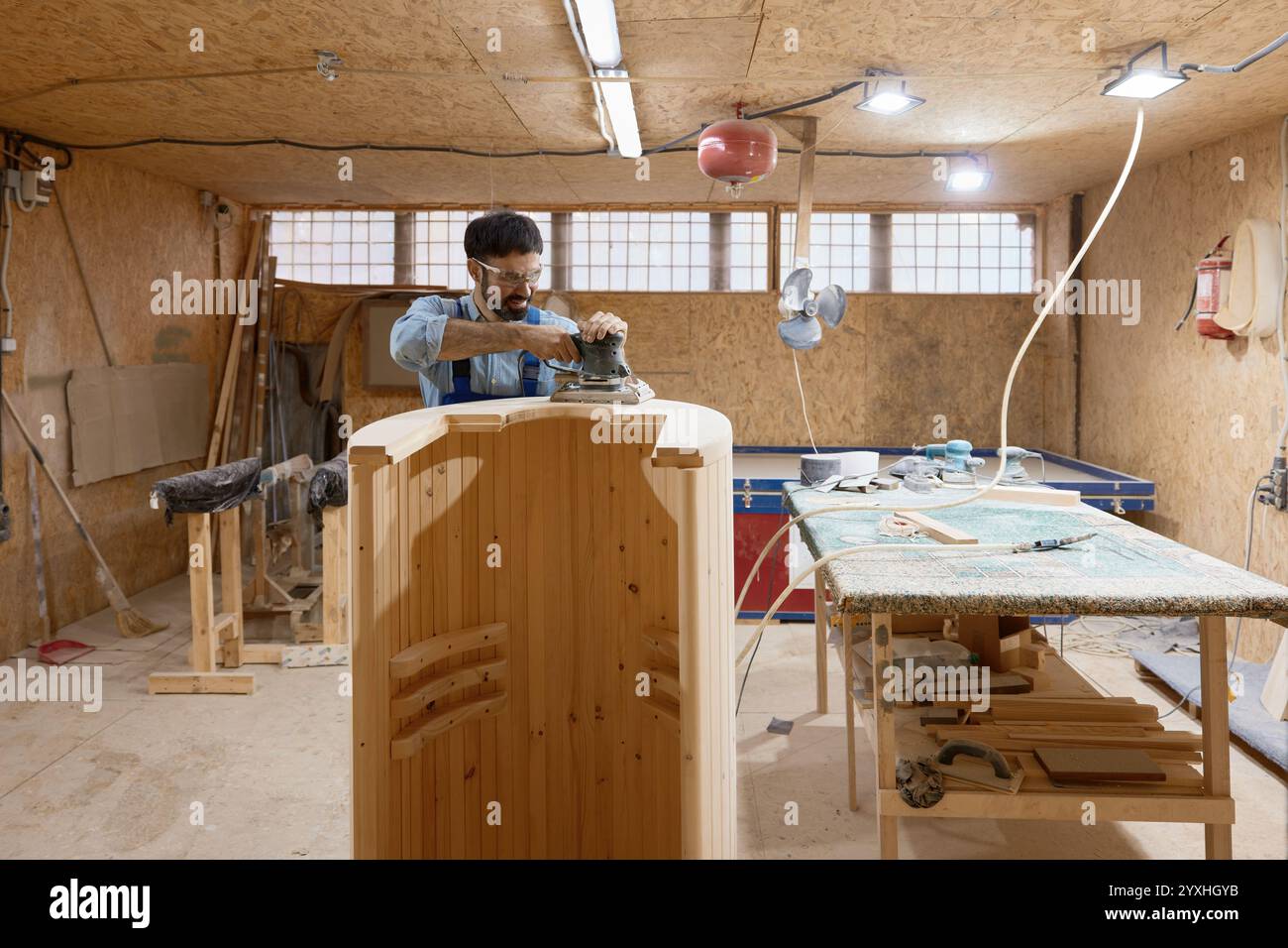 Carpentry studio worker using grinding machine for finishing wood ...