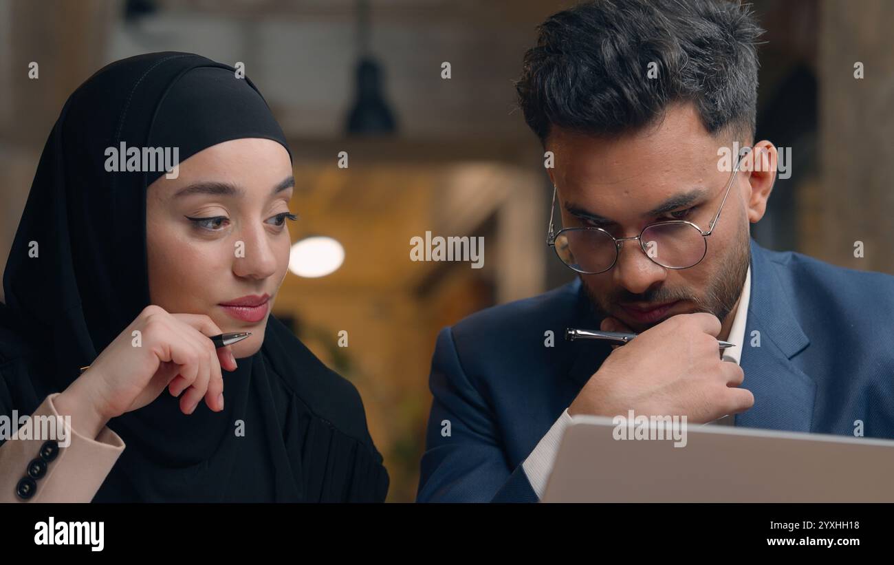 Two multiracial colleagues Arabian man muslim woman in hijab girl guy coworkers business ...