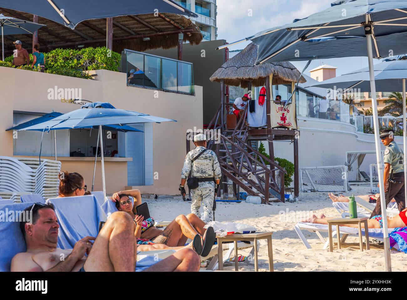 Armed military personnel patrol beach resort with lifeguard station and ...